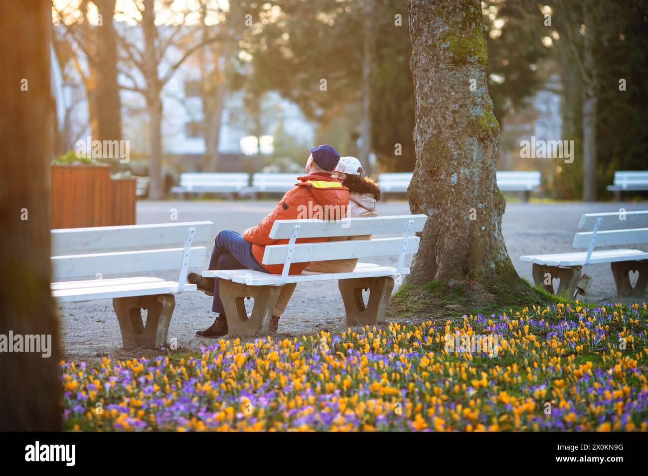 Spring, couple enjoying the first rays of sunshine on a park bench ...