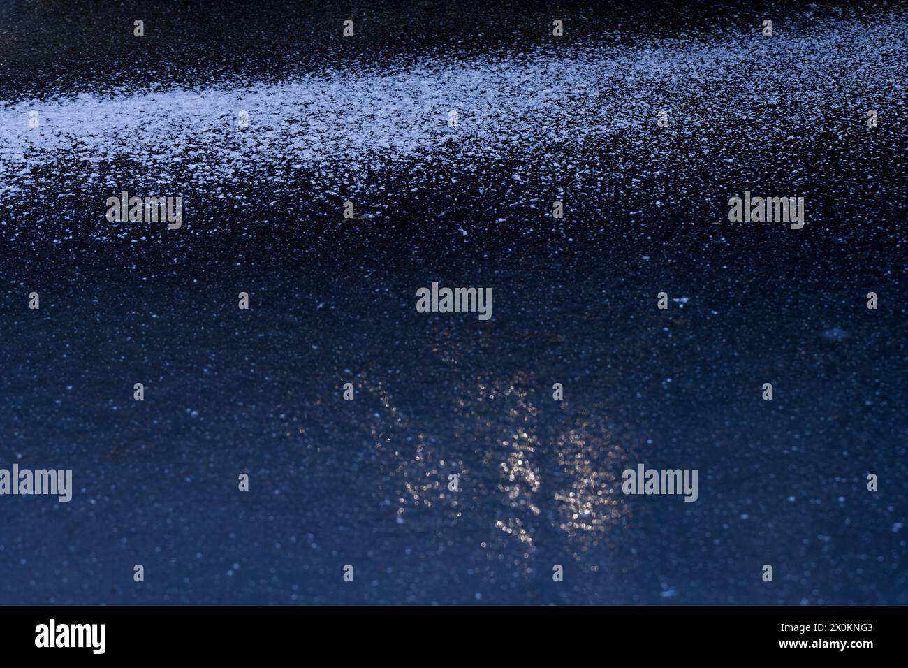 Ice layer on a lake, frost crystals cover part of the ice, light ...