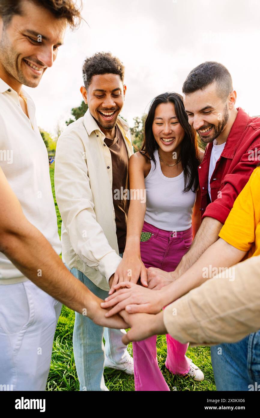 Multiracial young happy friends stacking hands at city park Stock Photo ...