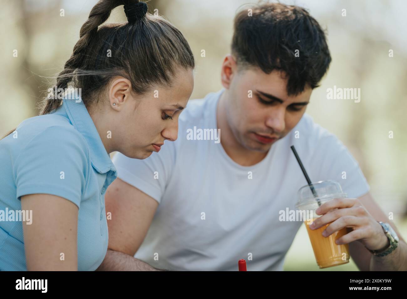 Focused high school friends studying together in a city park ...