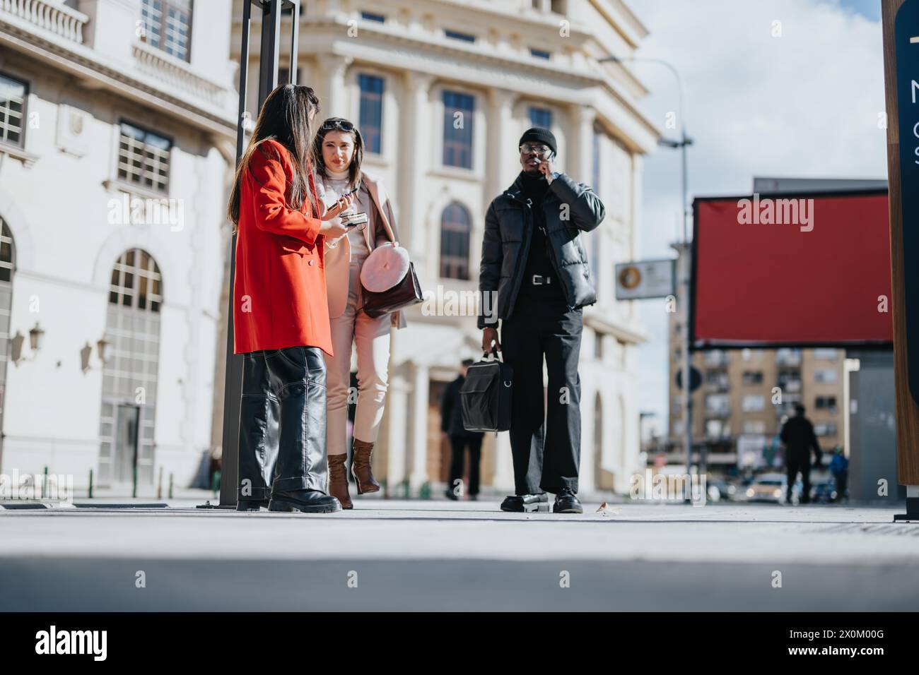 Three young business associates in a casual outdoor meeting. Two women ...