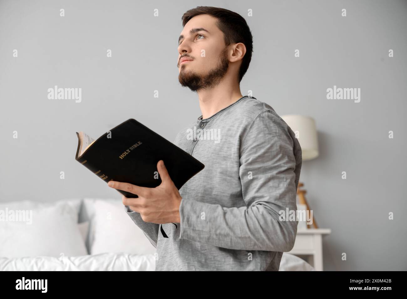 Young man reading Bible in bedroom Stock Photo - Alamy