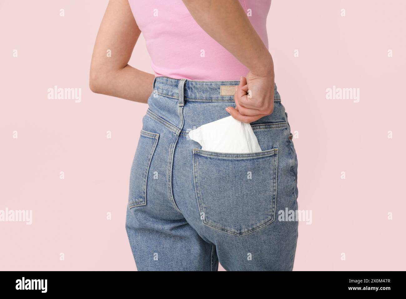 Woman putting menstrual pad into pocket on pink background Stock Photo ...
