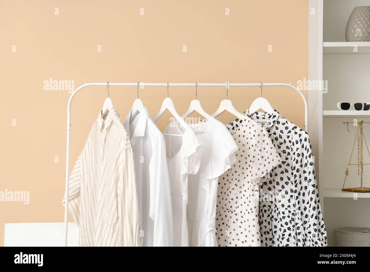 Stylish female clothes hanging on rack near color wall Stock Photo - Alamy