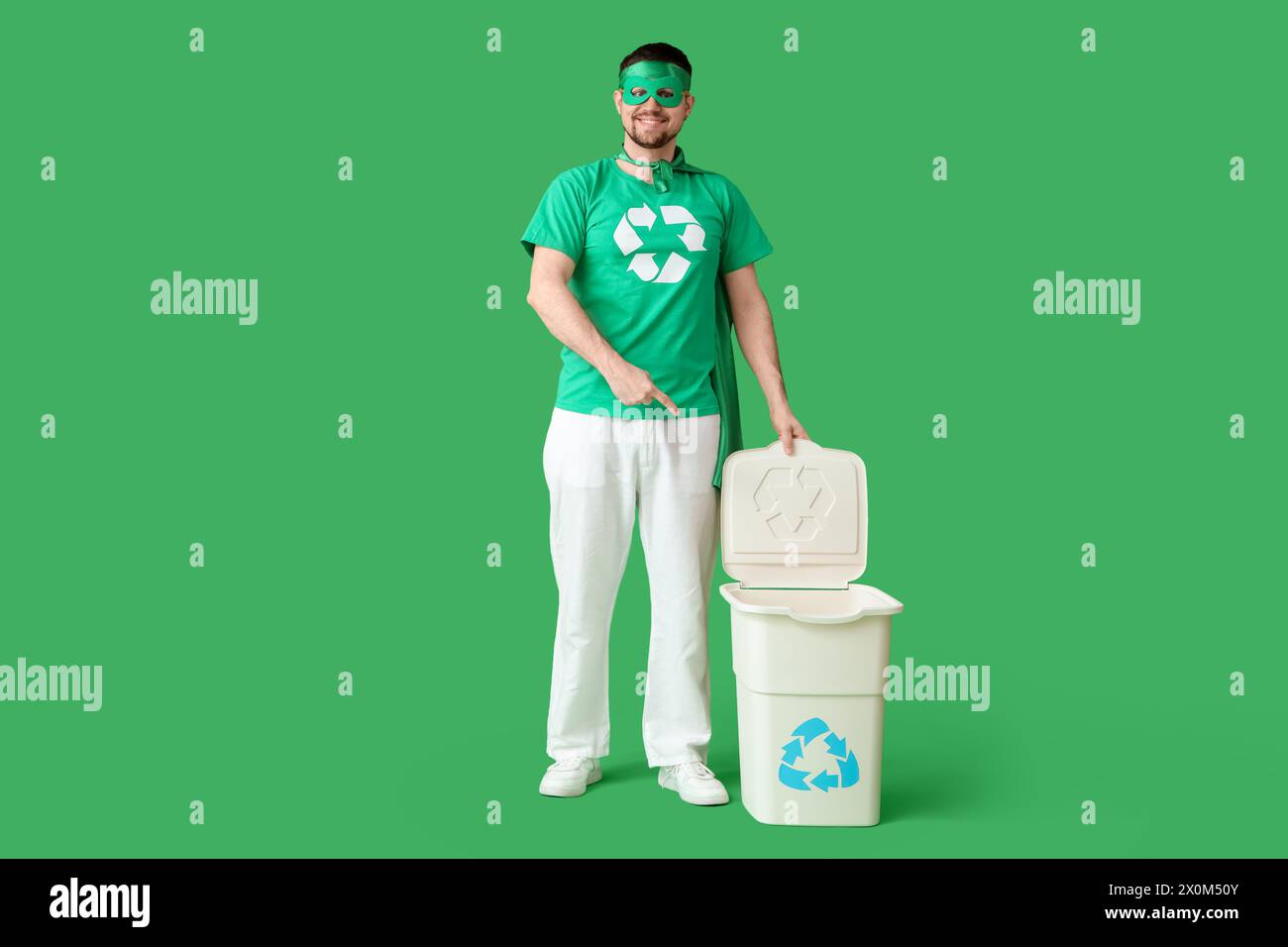 Young man dressed as eco superhero pointing at open garbage bin on ...