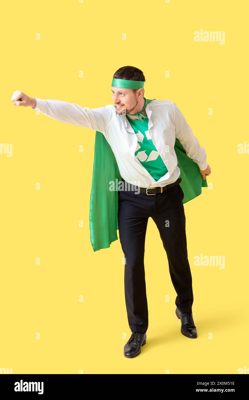 Young man dressed as eco superhero on yellow background. Ecology ...