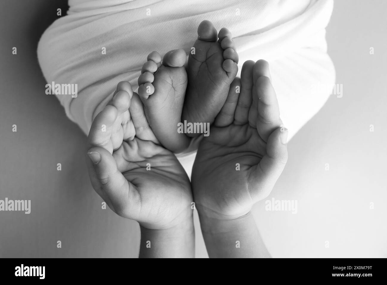 The palms of the father, the mother are holding the foot of the newborn ...