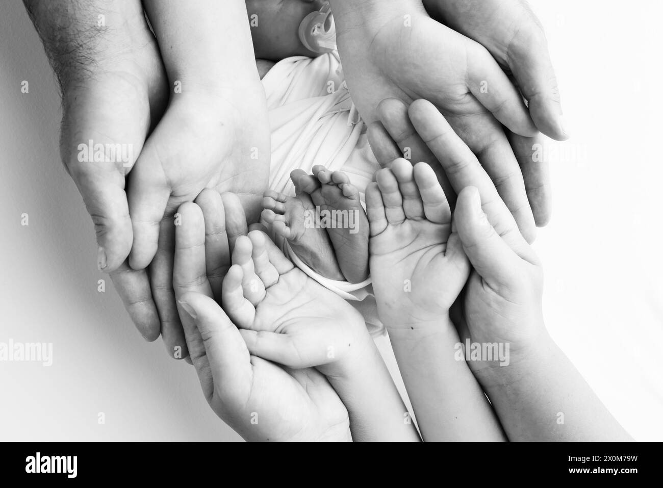 The palms of the father, the mother are holding the foot of the newborn ...