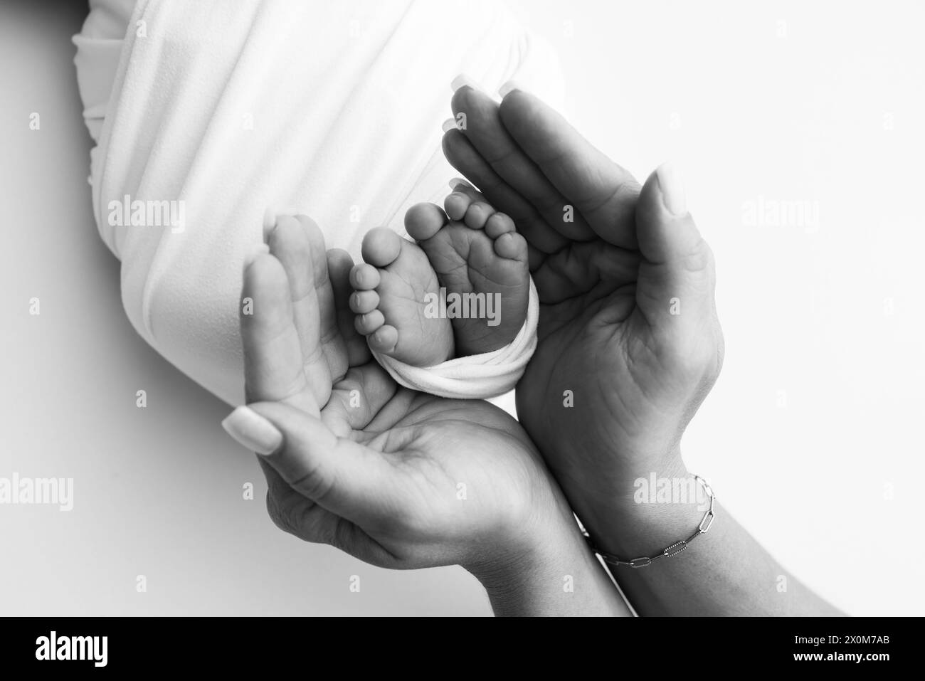 The palms of the father, the mother are holding the foot of the newborn ...