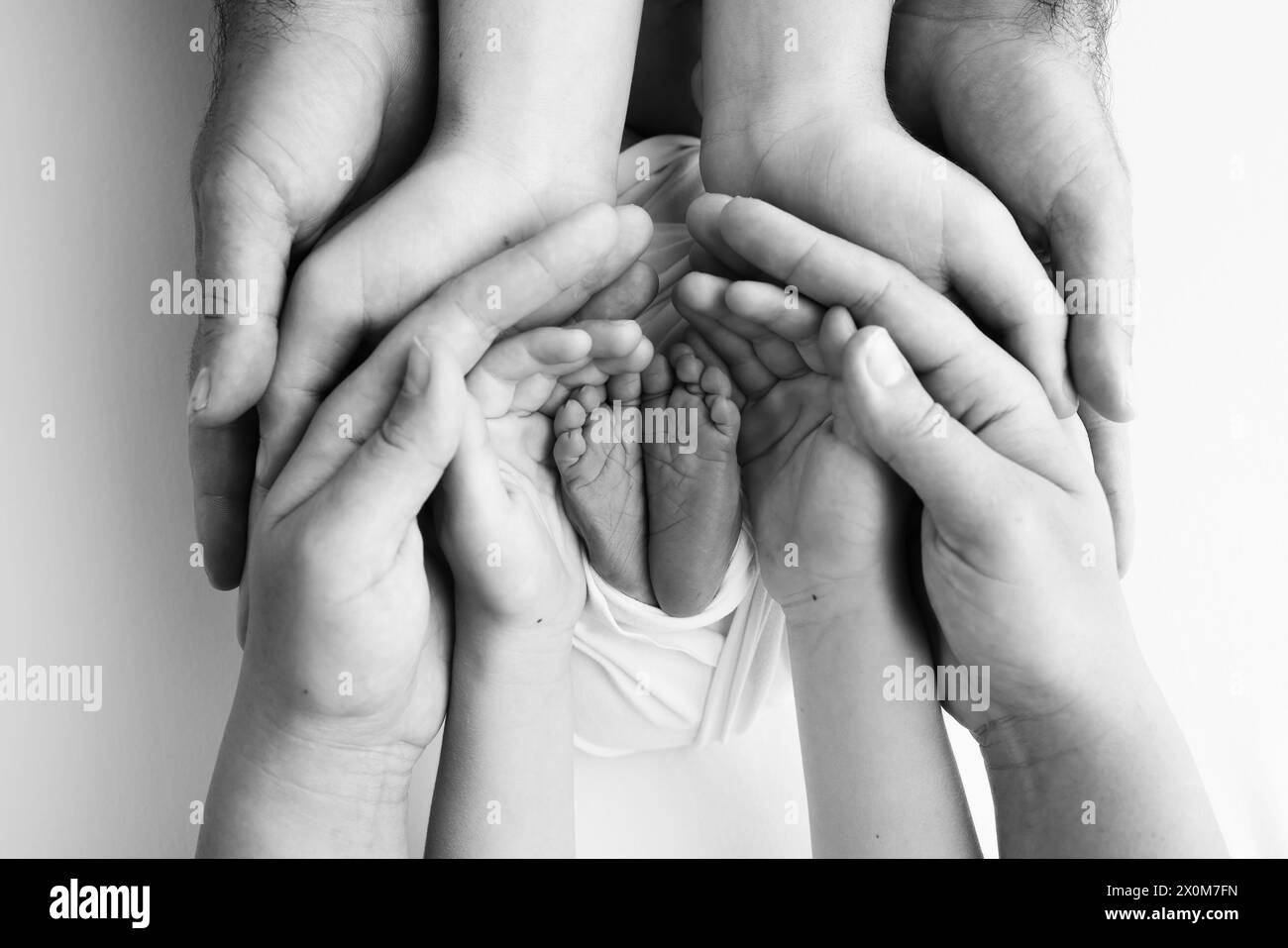 The palms of the father, the mother are holding the foot of the newborn ...