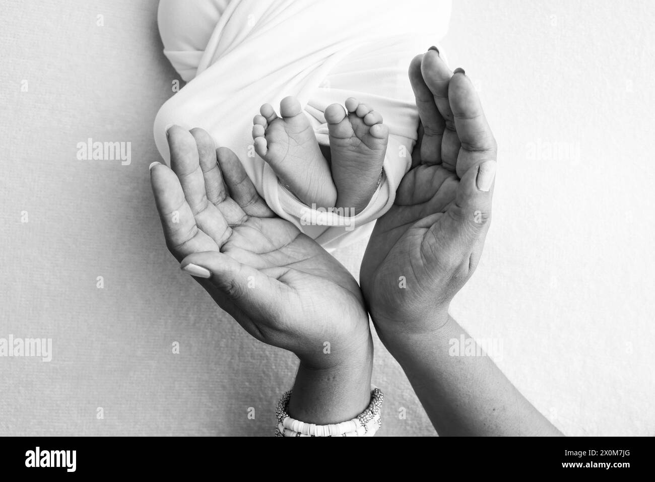 The palms of the father, the mother are holding the foot of the newborn ...