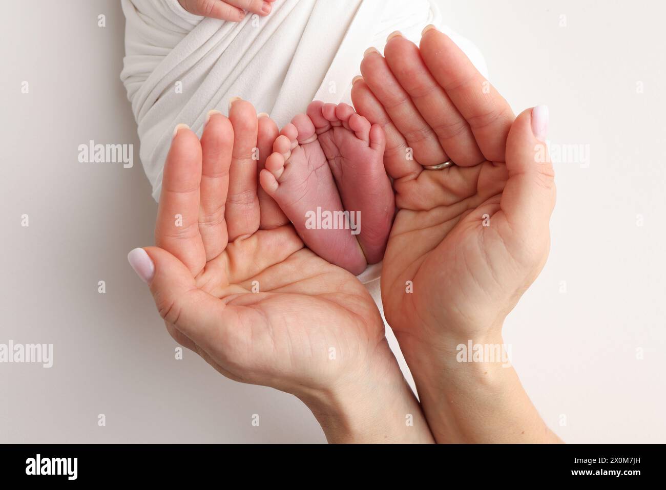 The palms of the father, the mother are holding the foot of the newborn ...