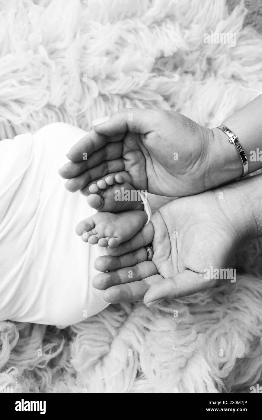 The palms of the father, the mother are holding the foot of the newborn ...
