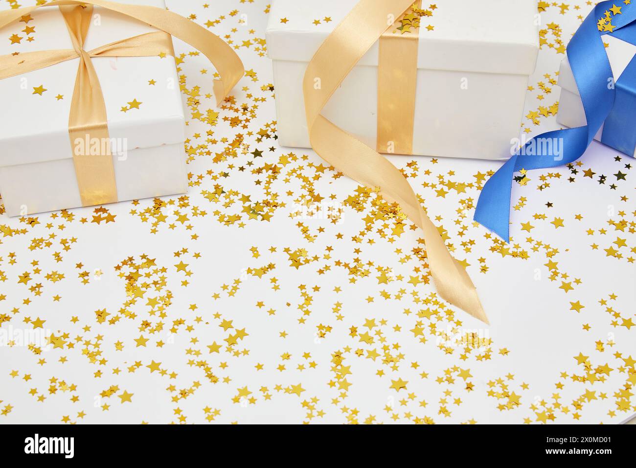 White wrapped gift boxes with gold and blue ribbons, and golden star ...