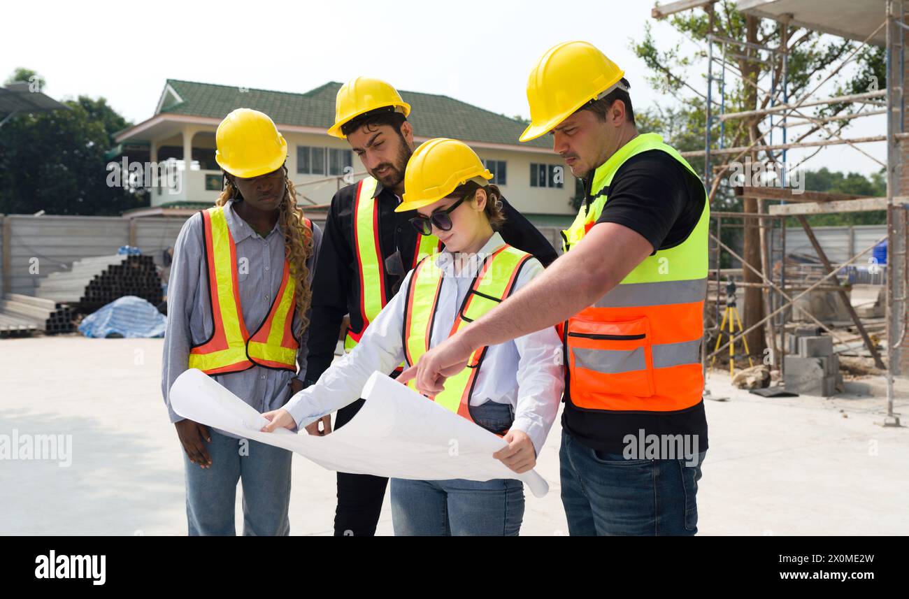 Group of construction workers gathered at a construction site reviewing ...
