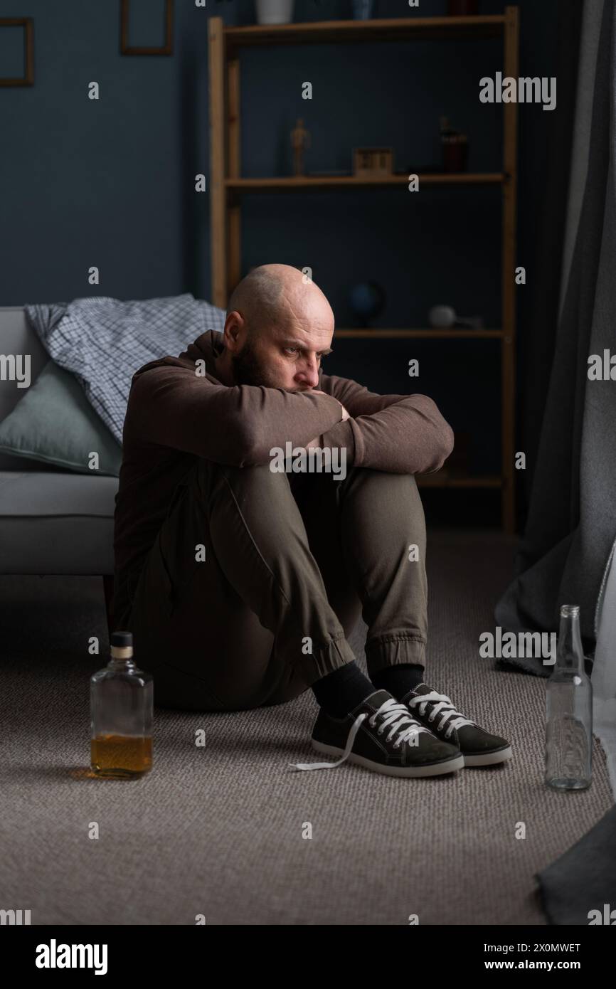 alcoholism and people concept. Bearded male alcoholic sitting on the ...