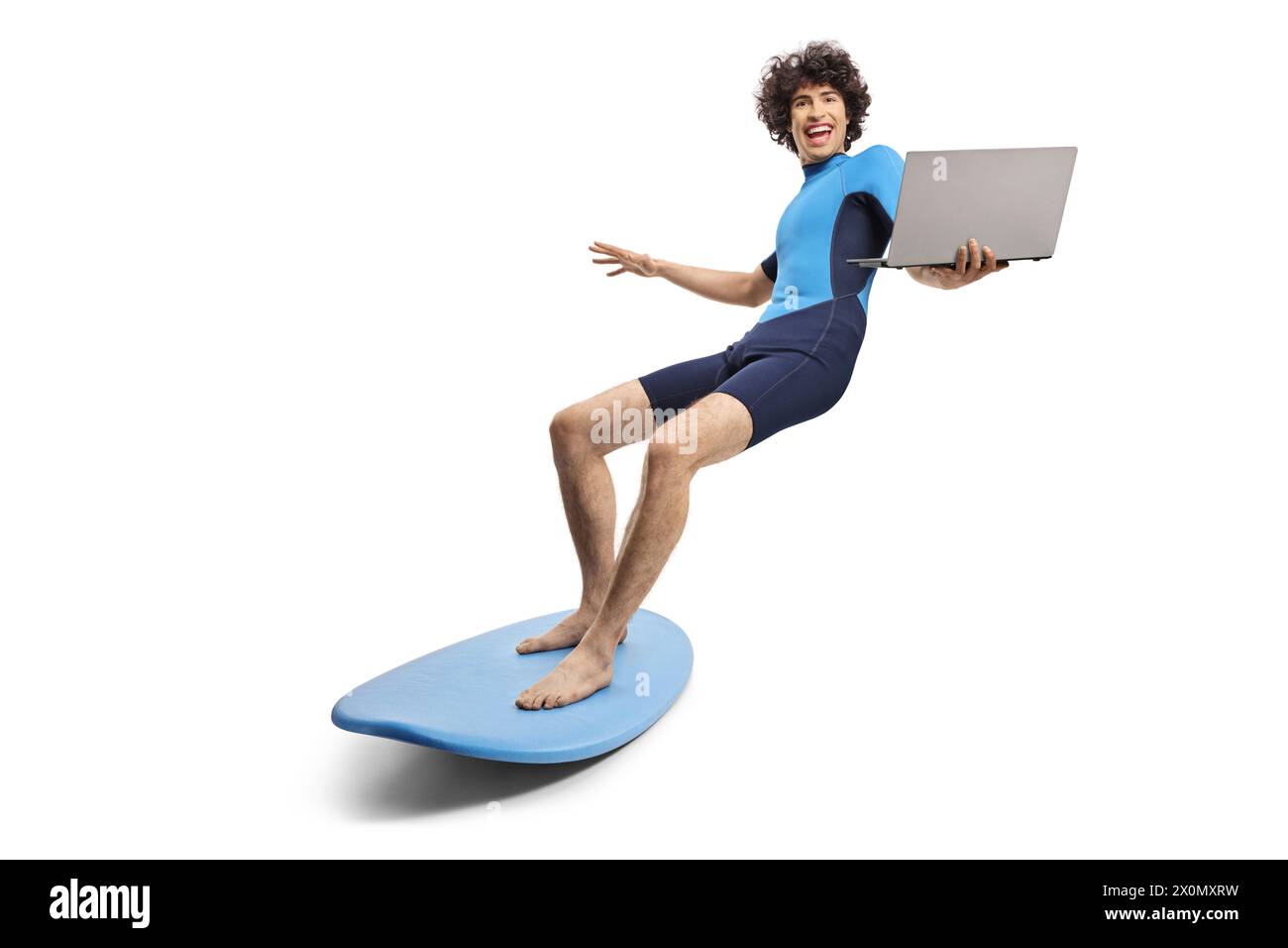 Young man in a wetsuit riding a surfboard and holding a laptop computer ...