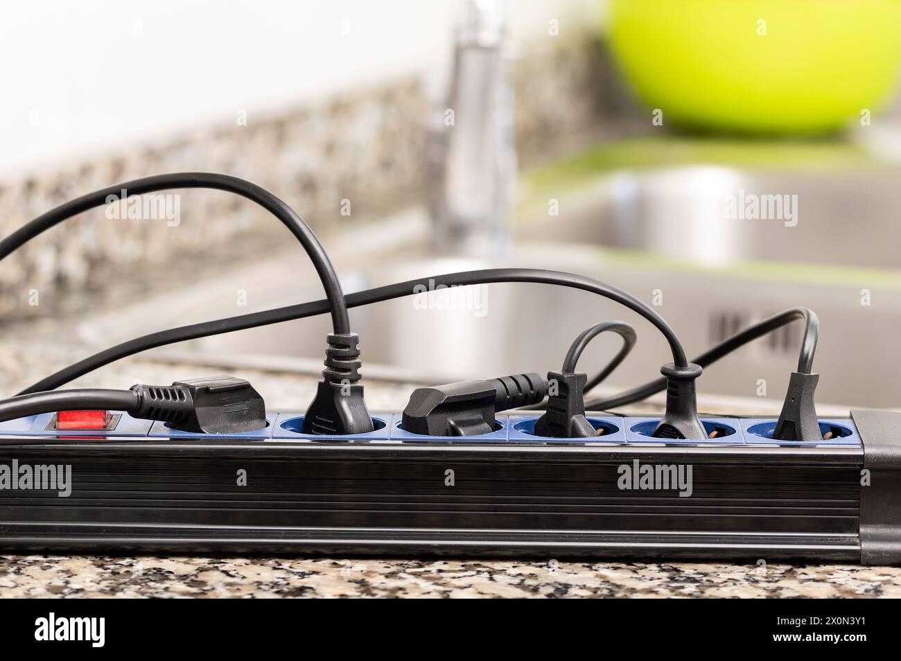 Close up of a plug in an electrical socket on a worktop at kitchen with ...