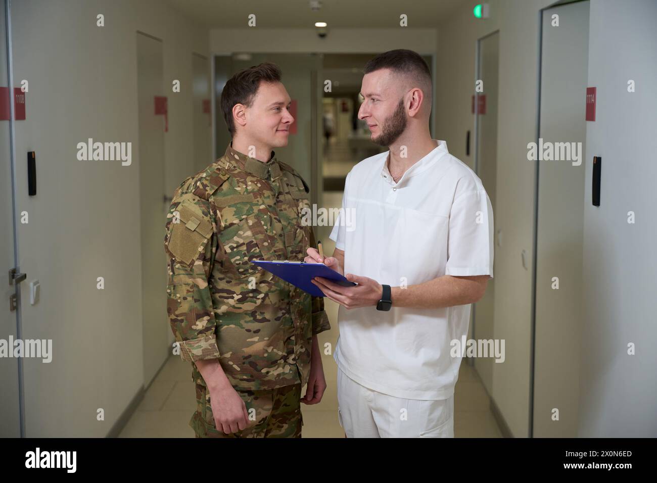 Physician making notes in hallway in presence of military patient Stock ...