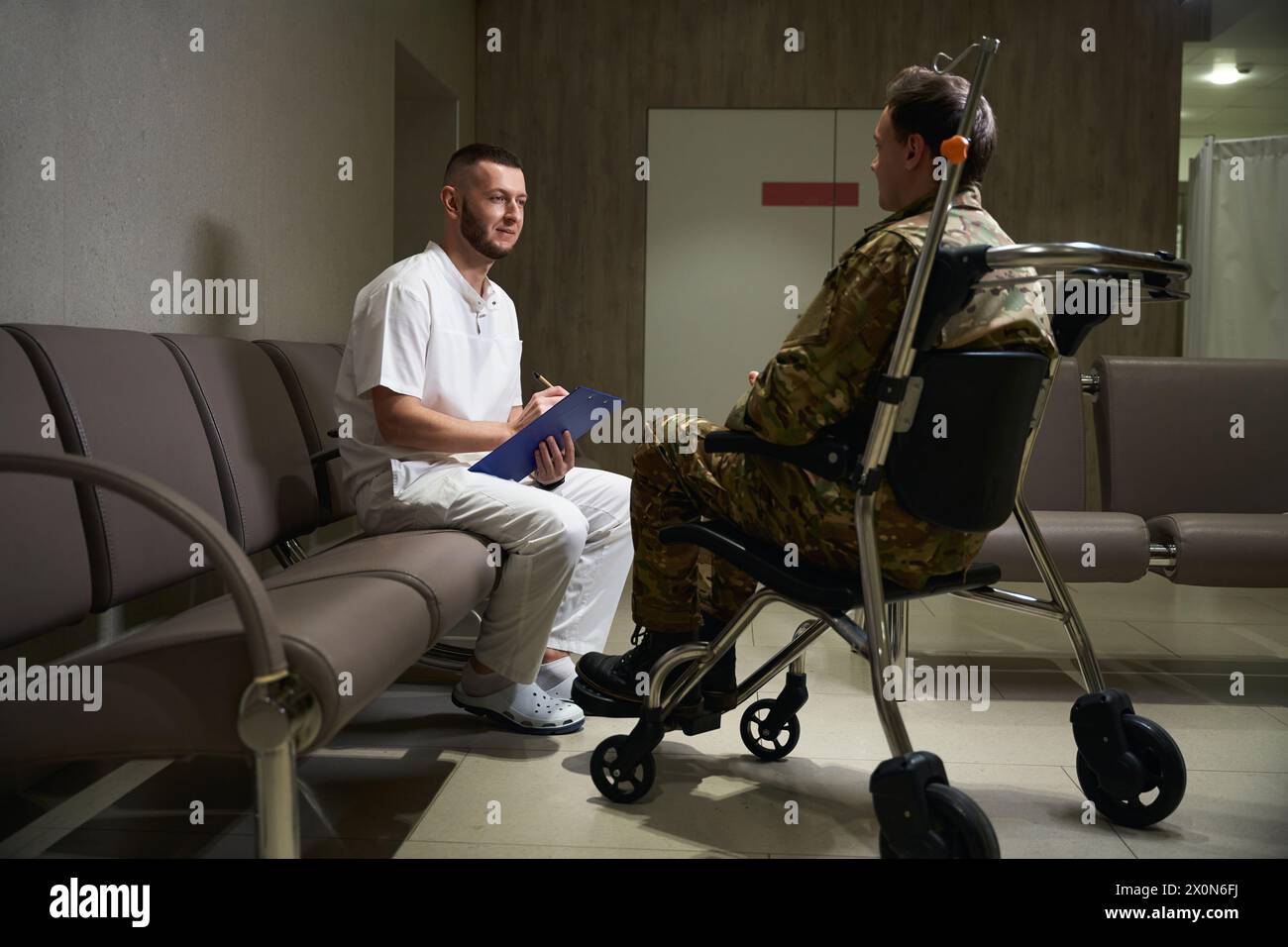 Doctor making notes of patient complaints in medical facility hall ...