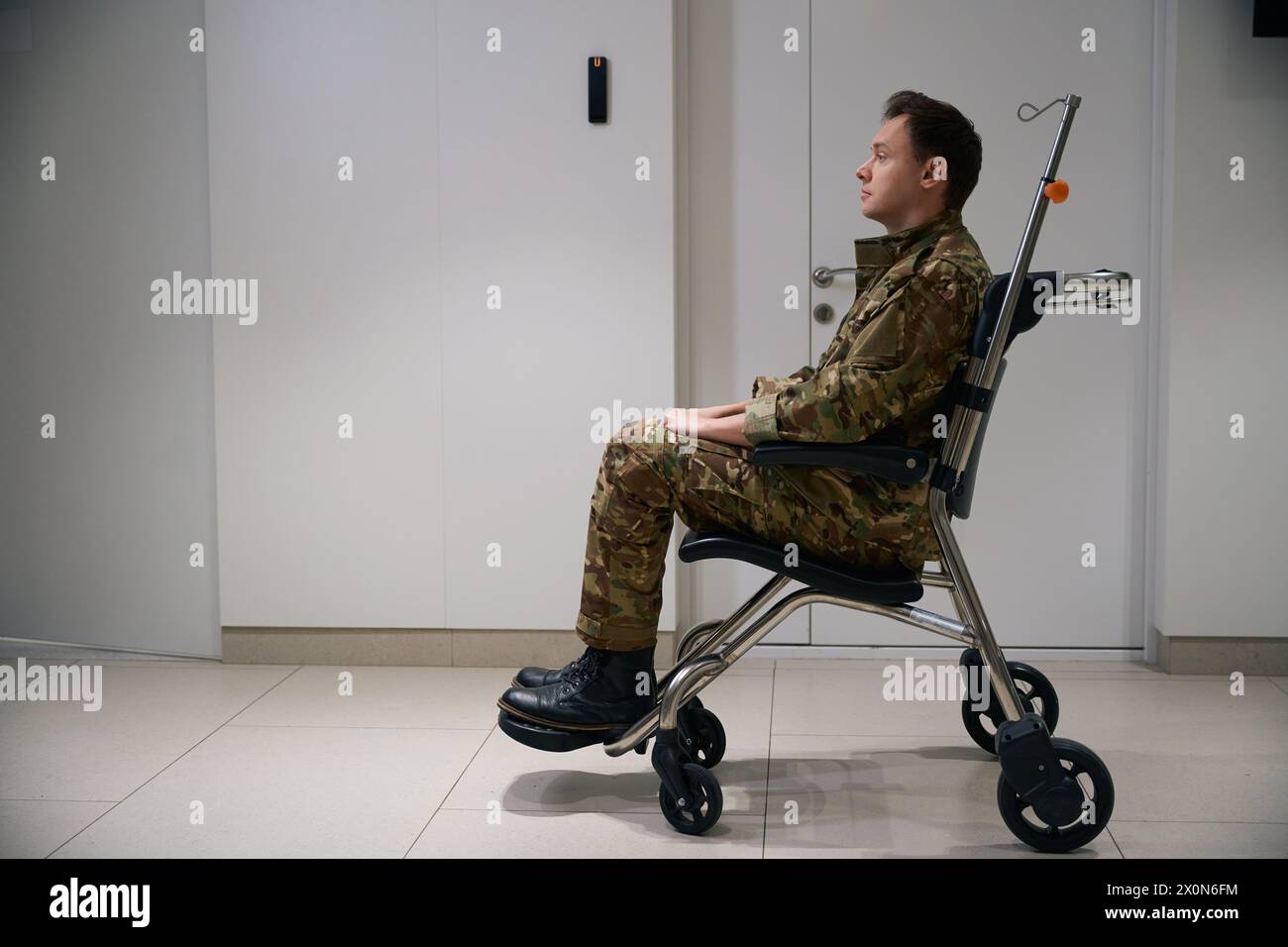 Serious serviceman with disability sitting in wheelchair in hospital ...