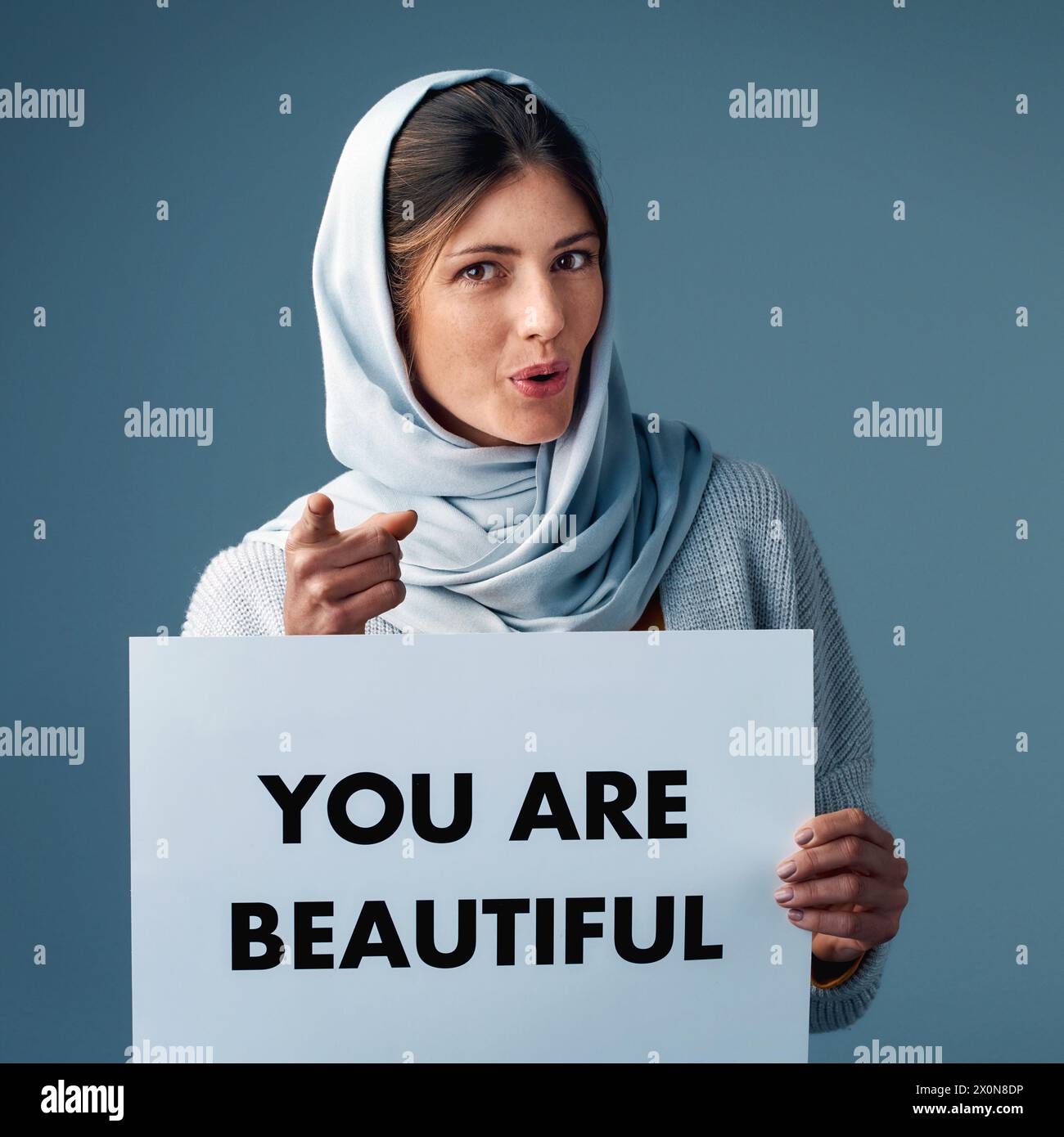 Muslim, woman and pointing with poster in studio on blue background for ...
