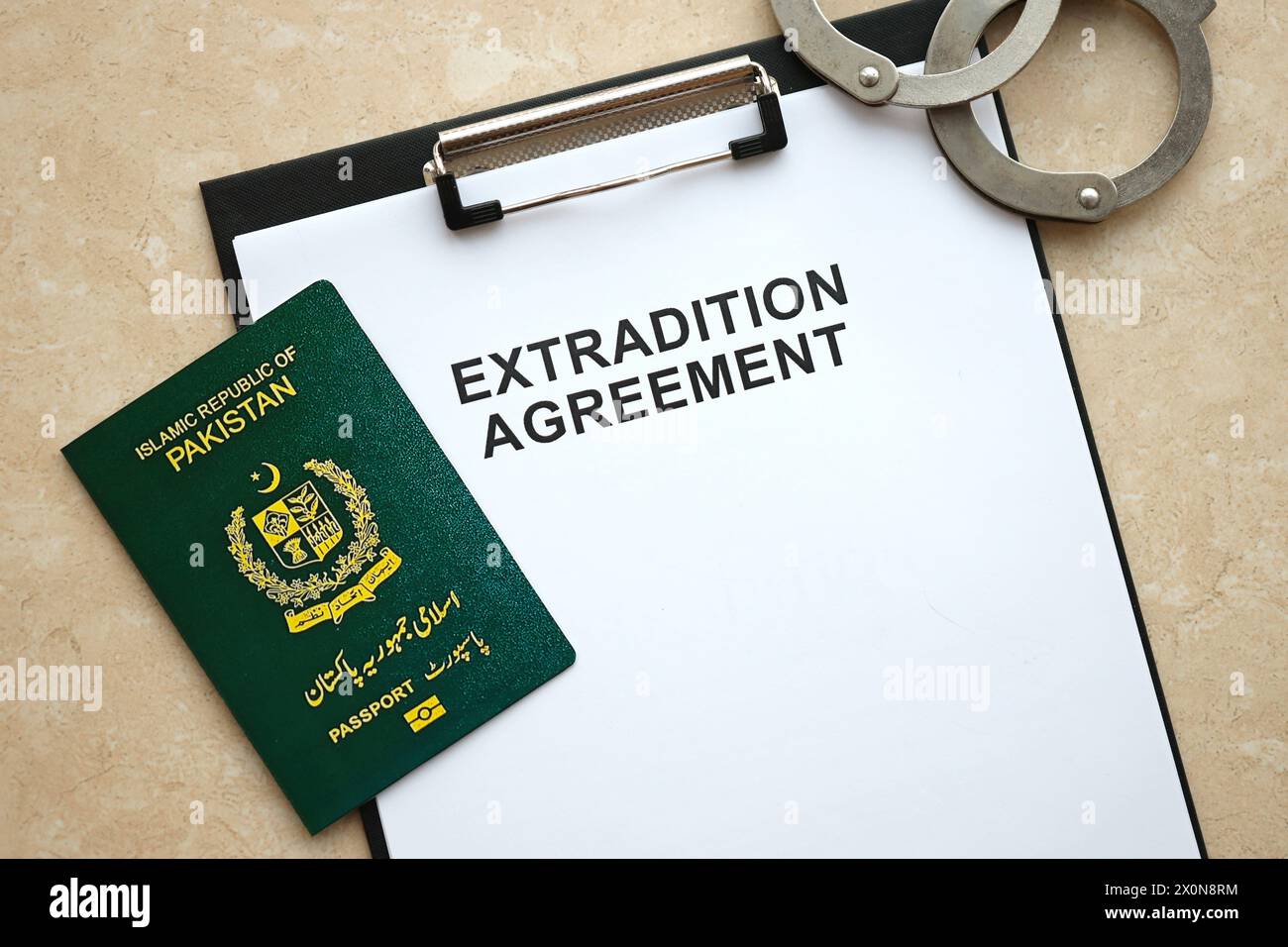 Passport of Pakistan and Extradition Agreement with handcuffs on table ...