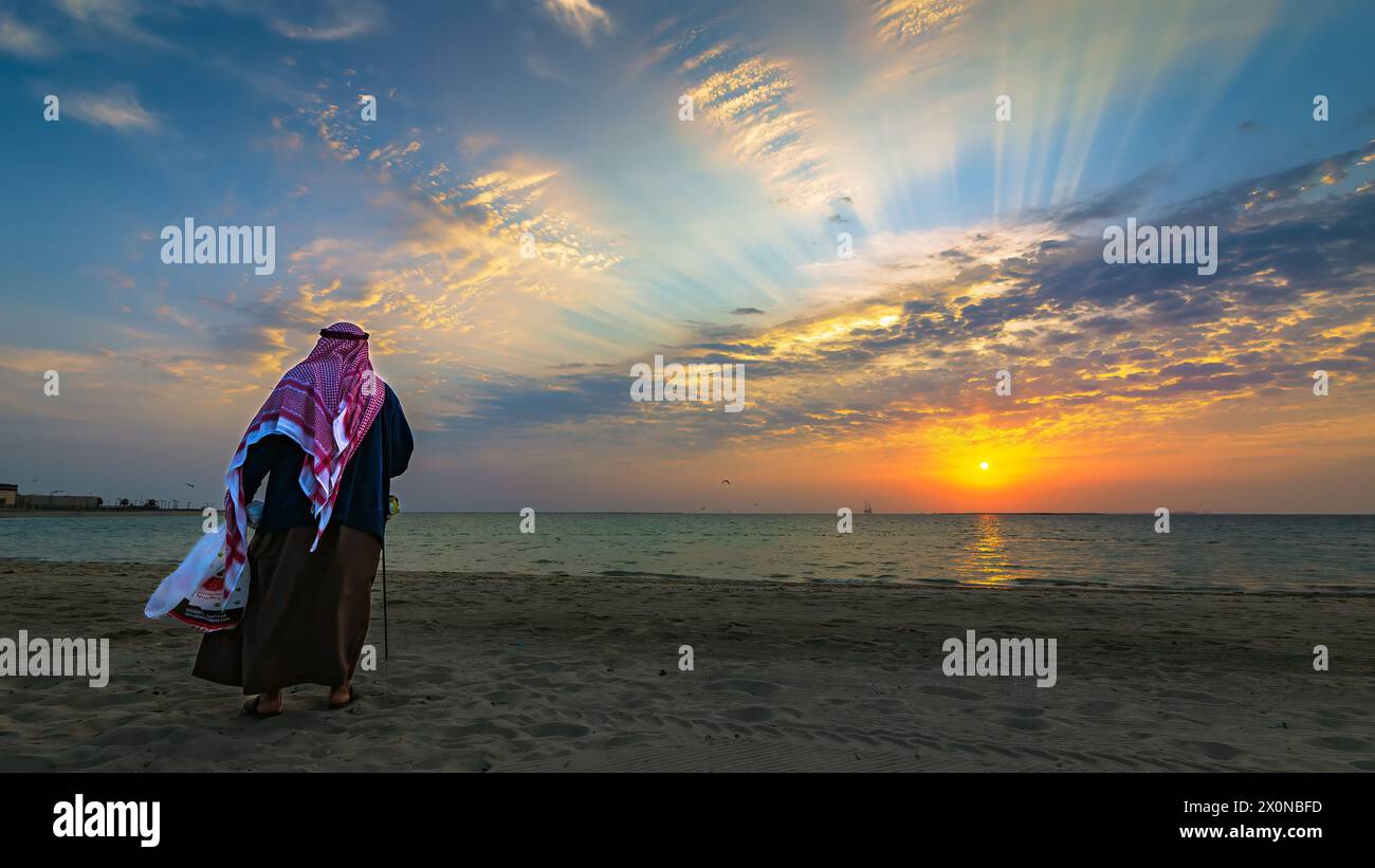 An elderly Arab man standing on Fanateer Beach with the sunrise in the ...