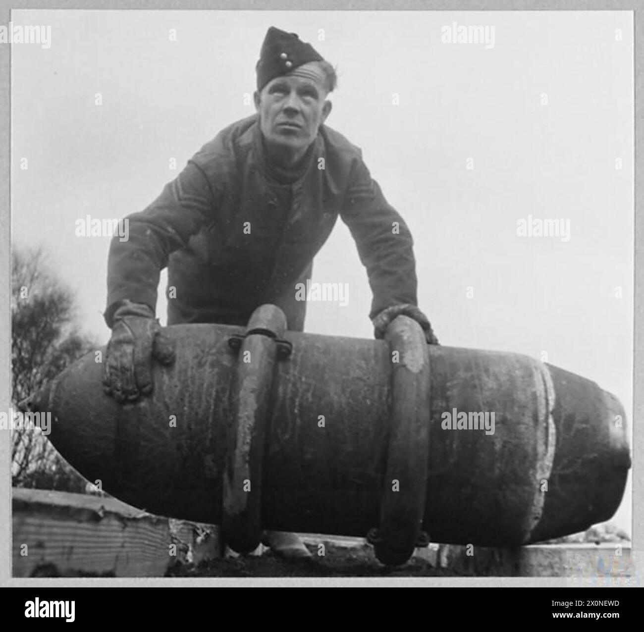 Photograph showing an RAF ground crew corporal rolling a 1000 lb. bomb ...