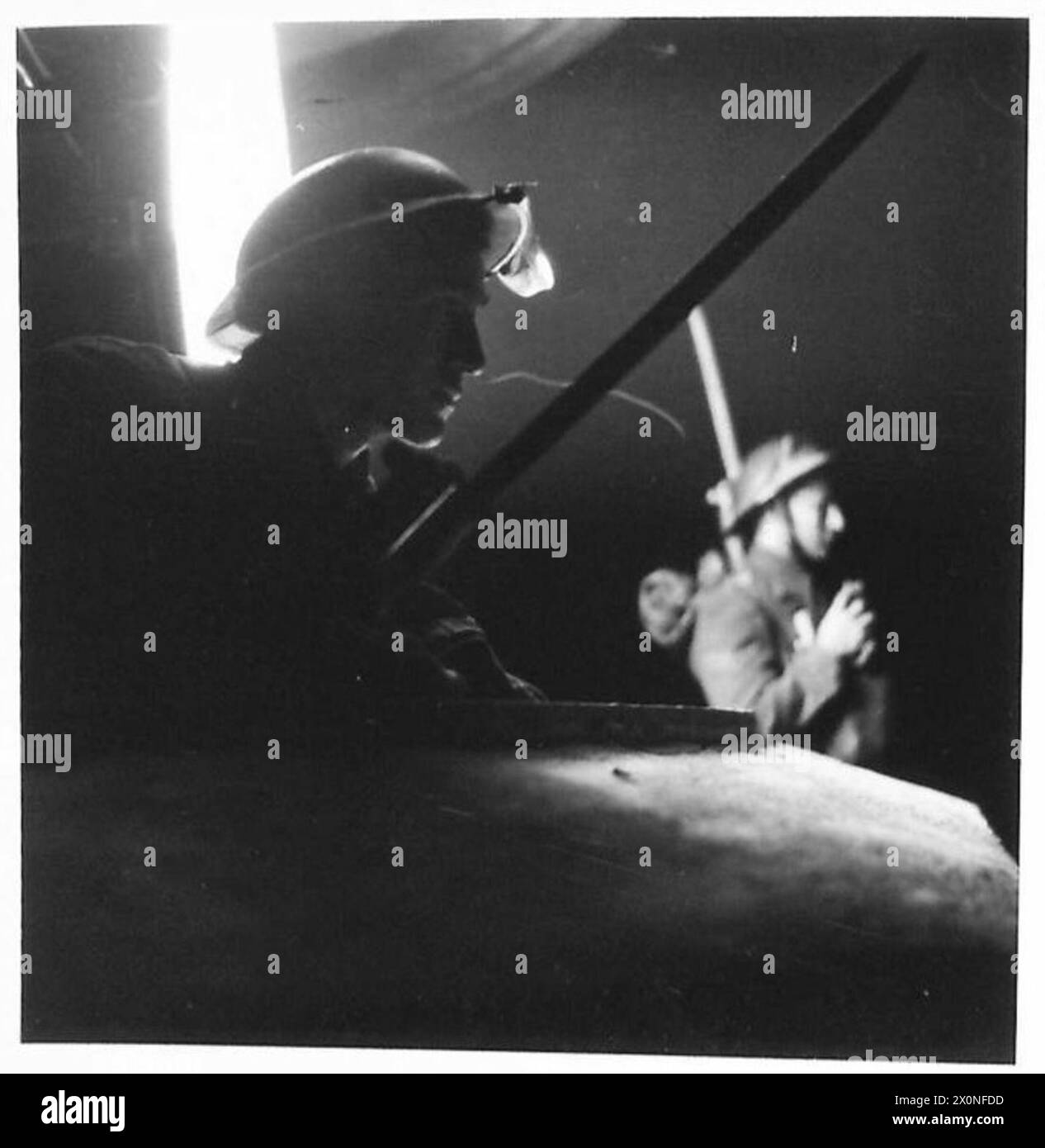 Men on duty monitor the seas as a searchlight scans the waters ...