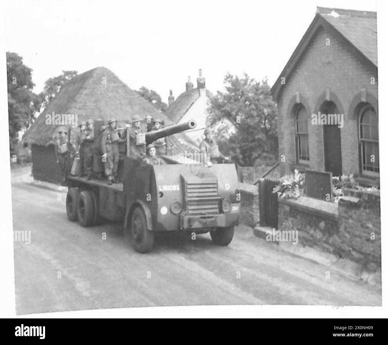 Photograph shows a 4-inch naval gun mounted on a lorry moving through a ...