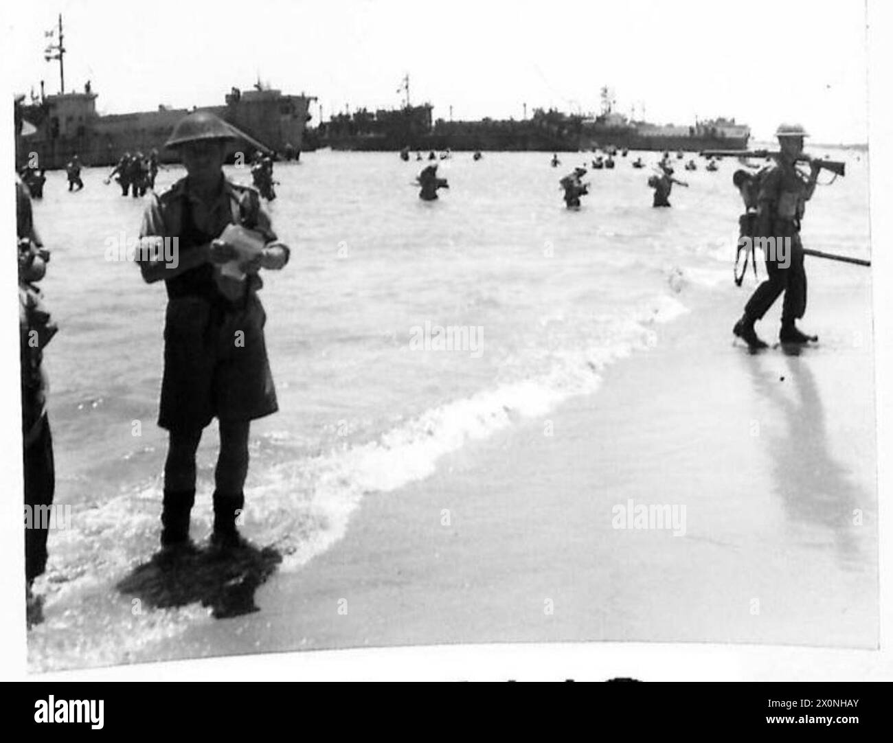 Photograph showing infantry soldiers wading ashore from landing craft ...