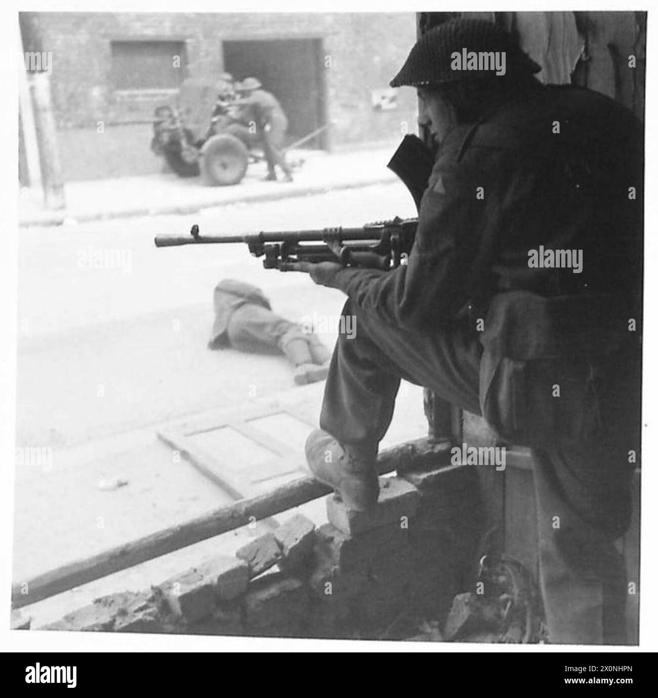 A Bren gunner operates from a demolished building to cover advancing ...
