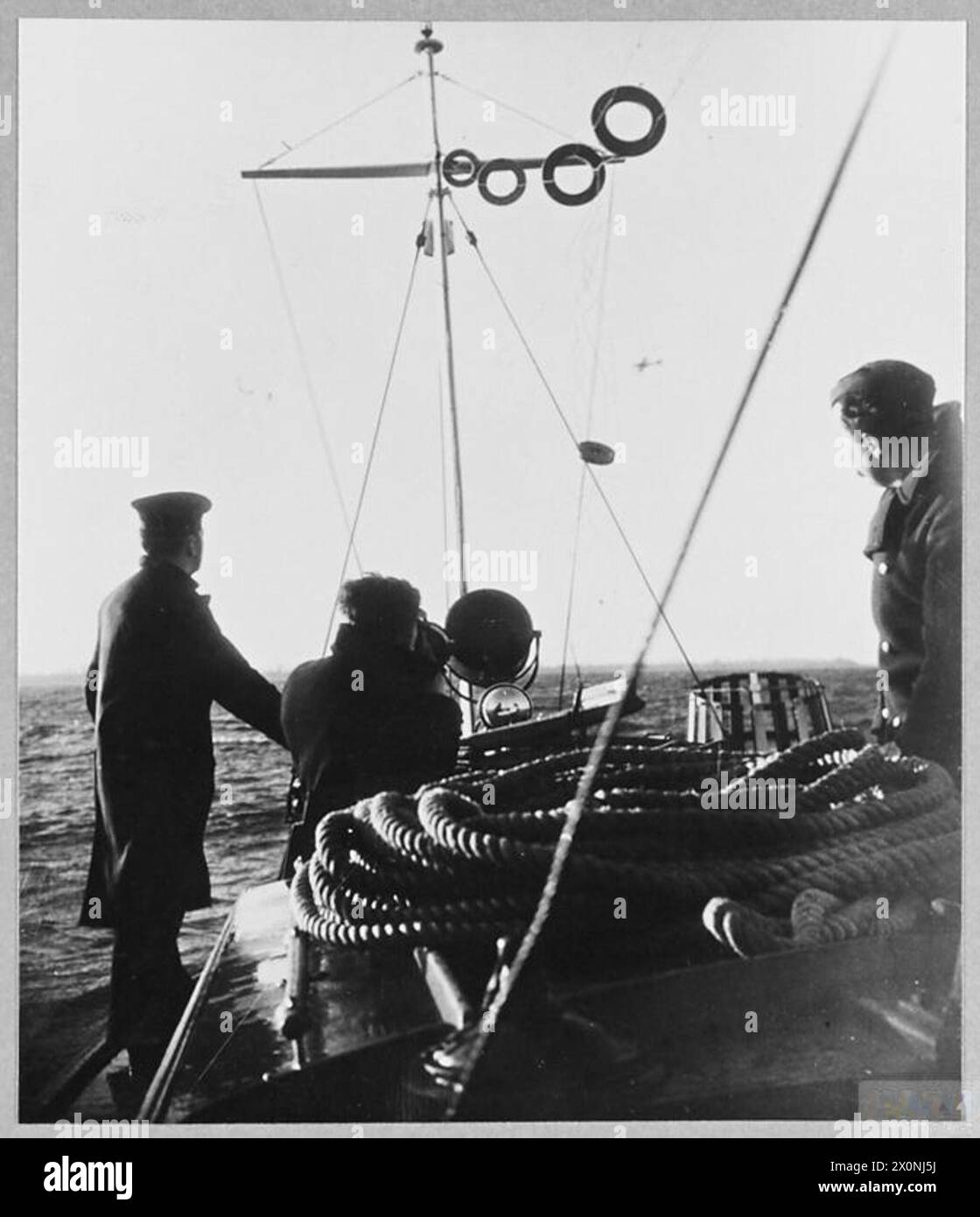 A naval signaller uses an Aldis lamp to transmit a message to a Coastal ...
