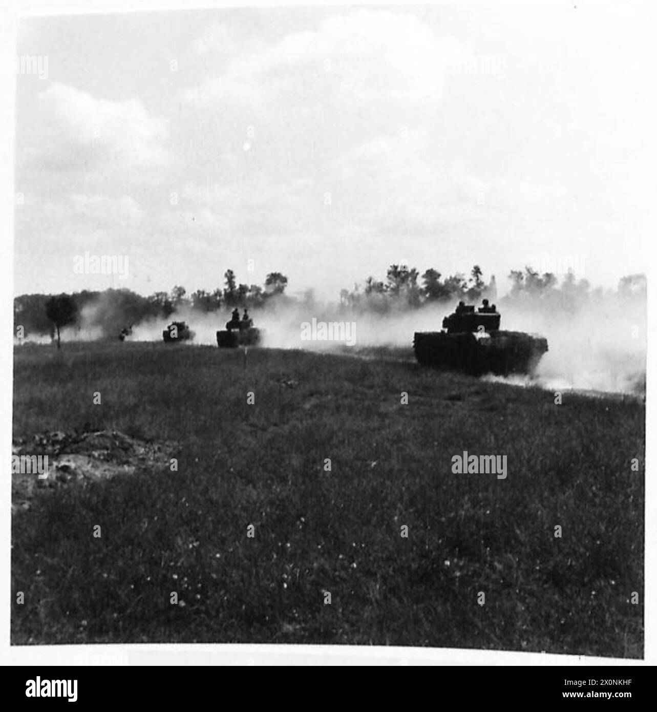 Churchill tanks of a British crew move across fields and dusty roads in ...