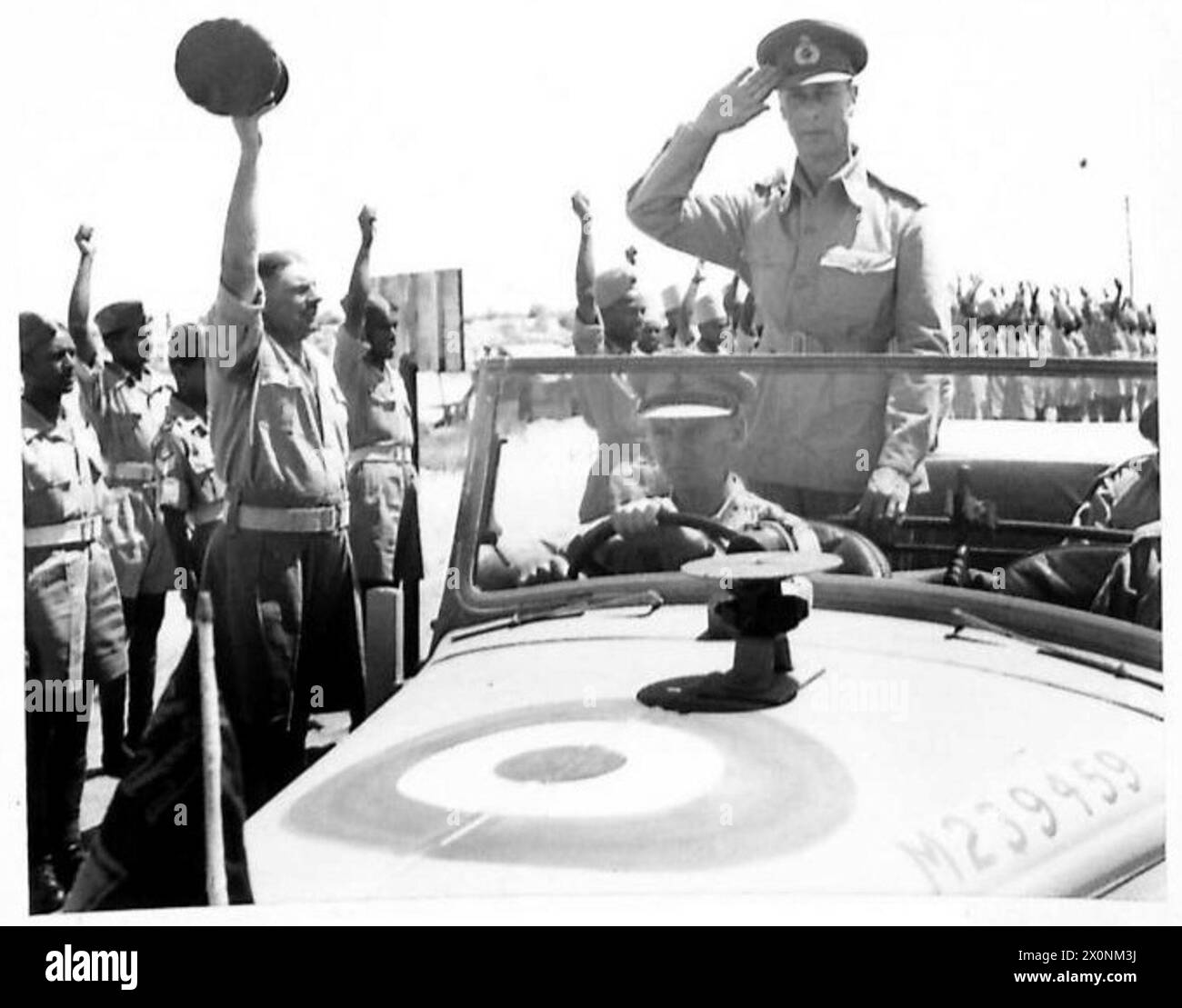 WITH THE EIGHTH ARMY - His Majesty saluting as he drives through lines ...