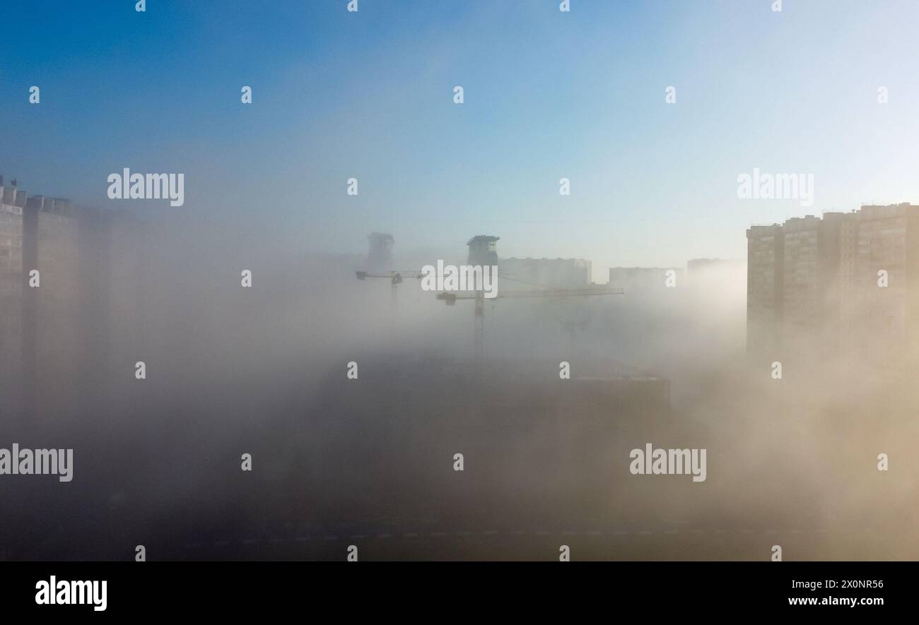 Construction cranes and a multi-storey residential building, shrouded ...