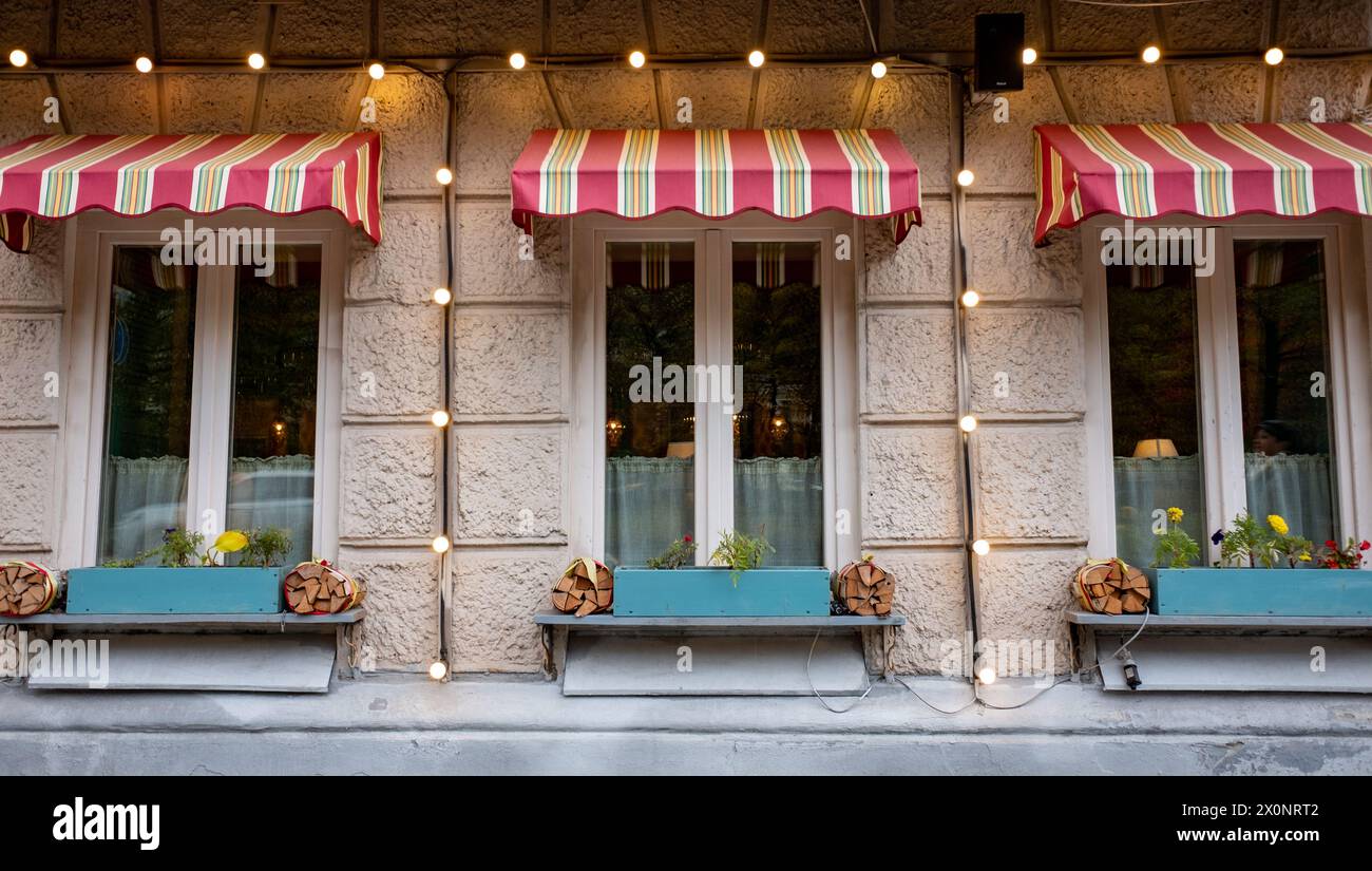 flowers on the window sills of three windows of a street cafe in the ...