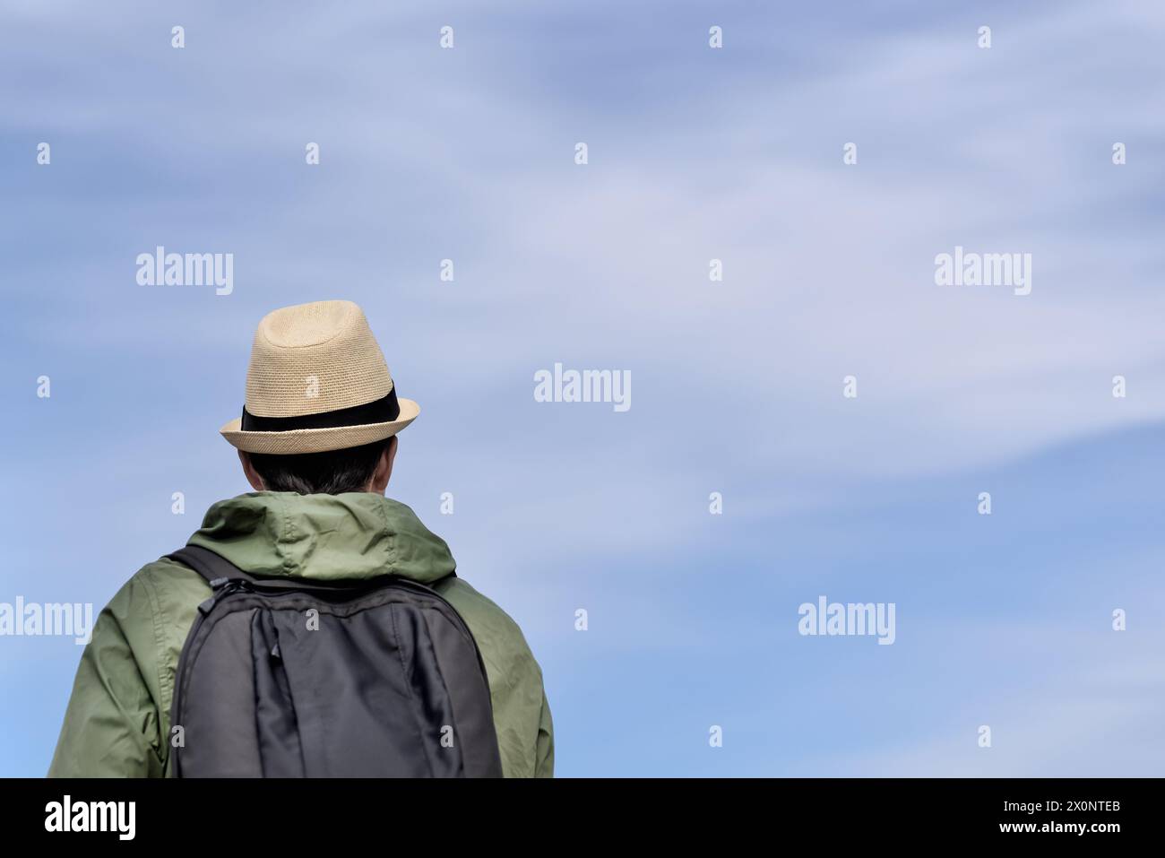 Back view of a traveler man with a backpack against the blue sky with ...