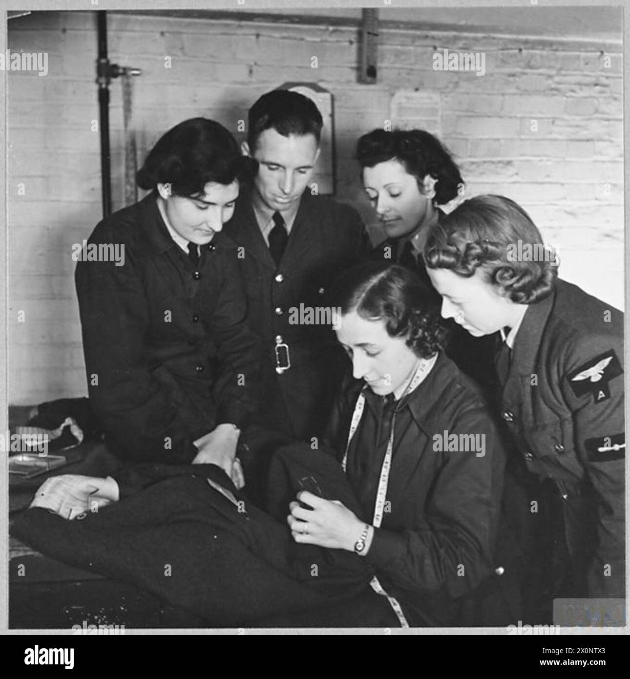 A W.A.A.F. tailoress demonstrates garment alterations as part of ...