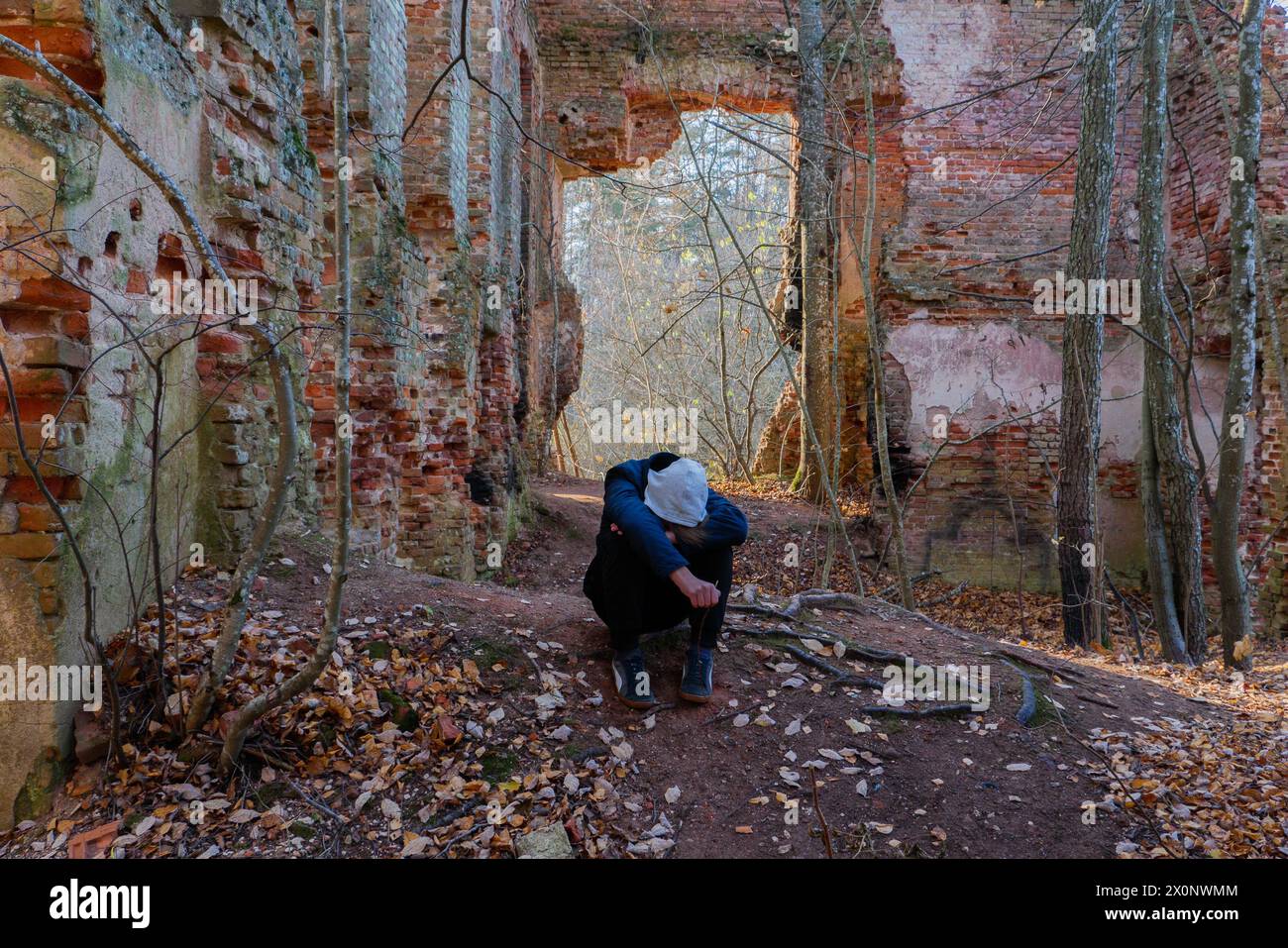 The boy dropped his head to his knees. A teenager sits in an abandoned ...
