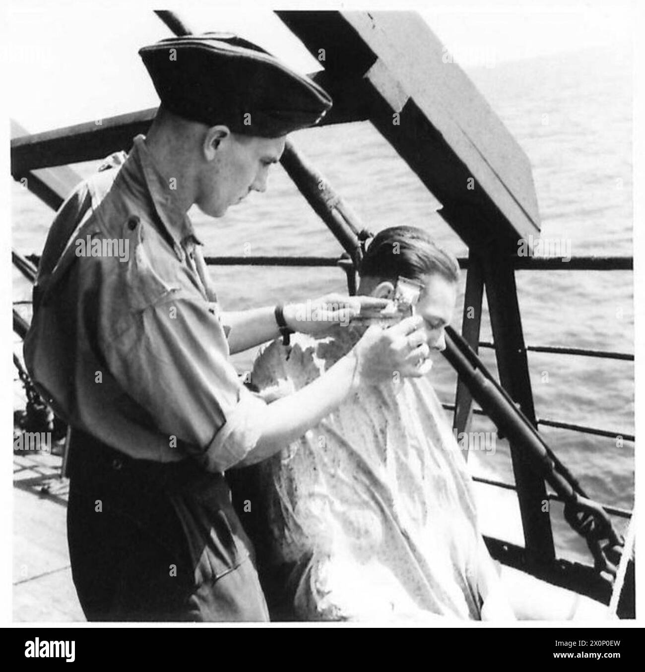 A soldier gives a friend a haircut on a troop ship during a convoy to ...