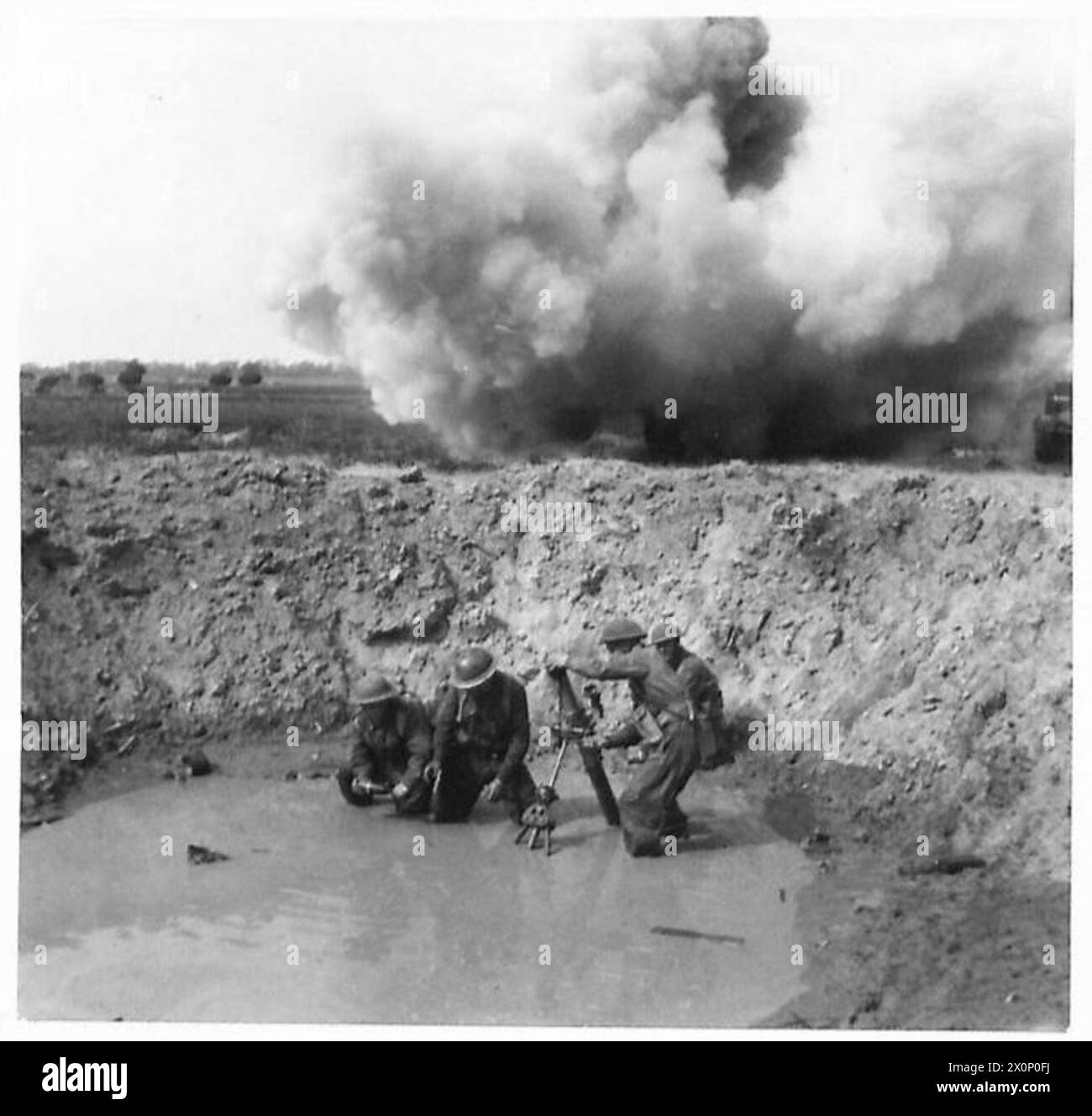 Fifth Army troops use the water-filled bomb crater as cover while under ...