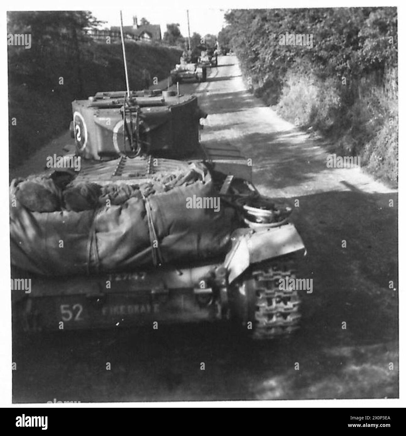 A convoy of Mk.III Infantry Valentine tanks moves along a country road ...