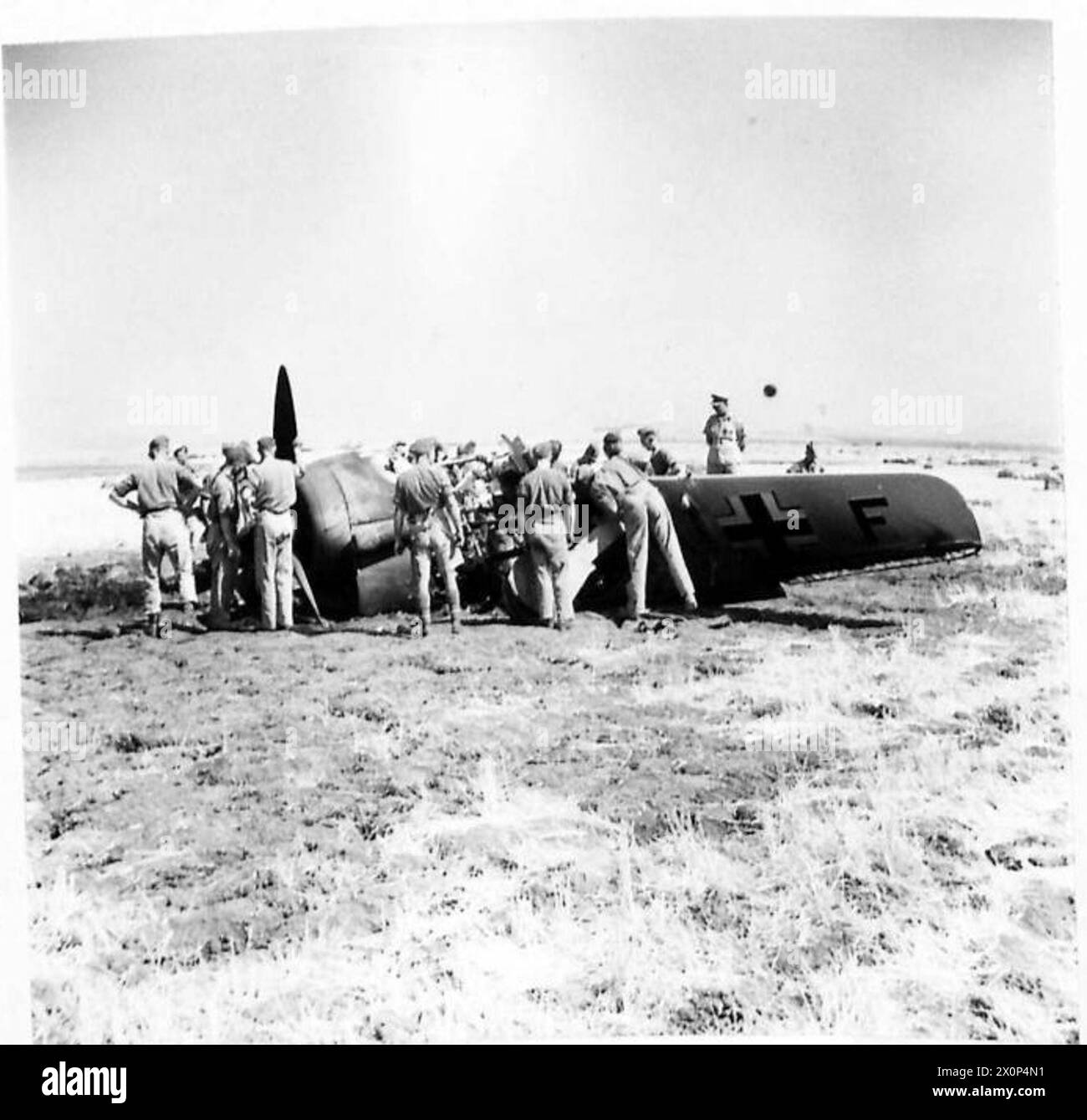 A destroyed Focke-Wulf aircraft draws attention from British troops in ...