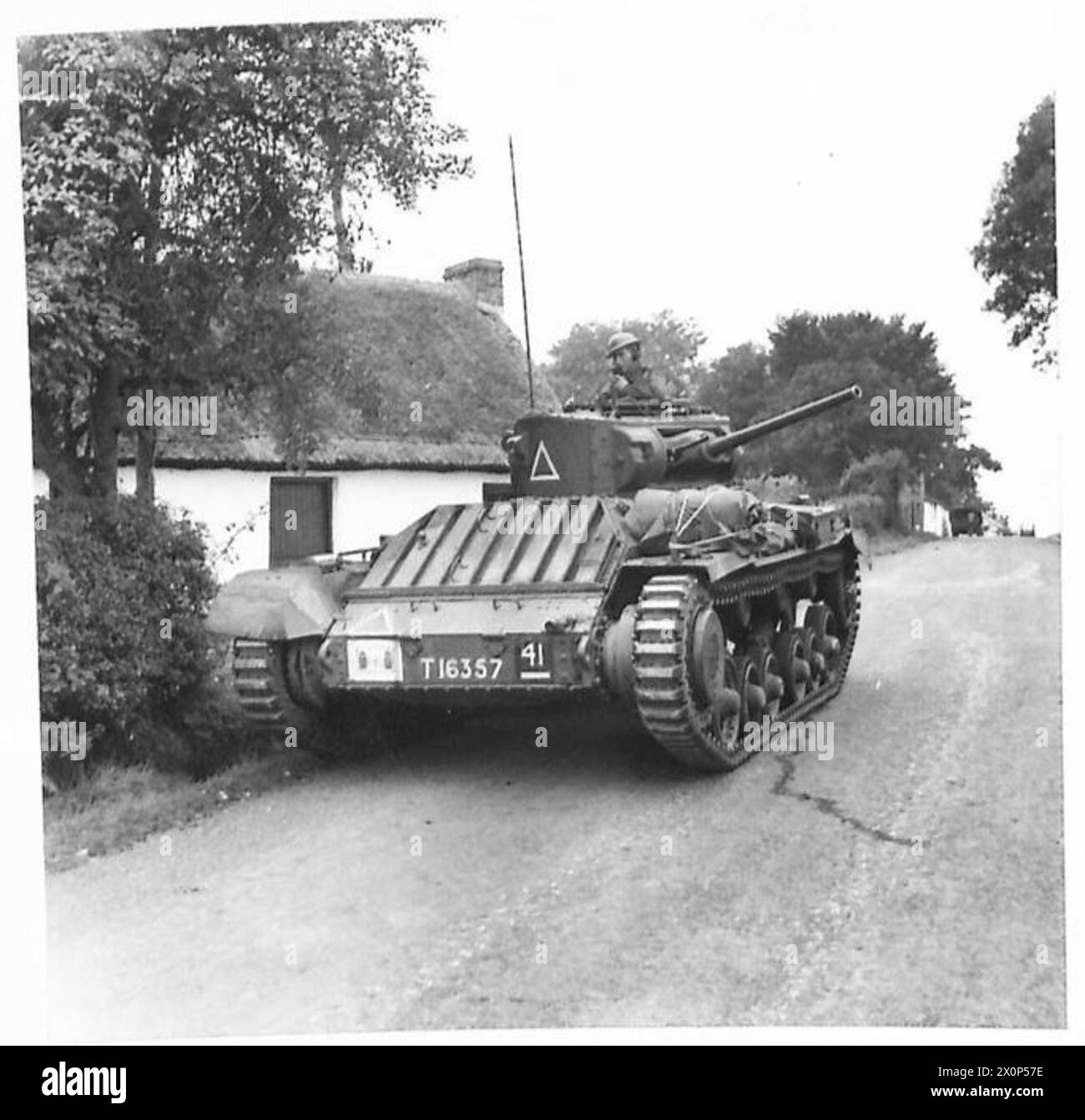 A Valentine tank is halted beside a traditional Irish cottage during an ...