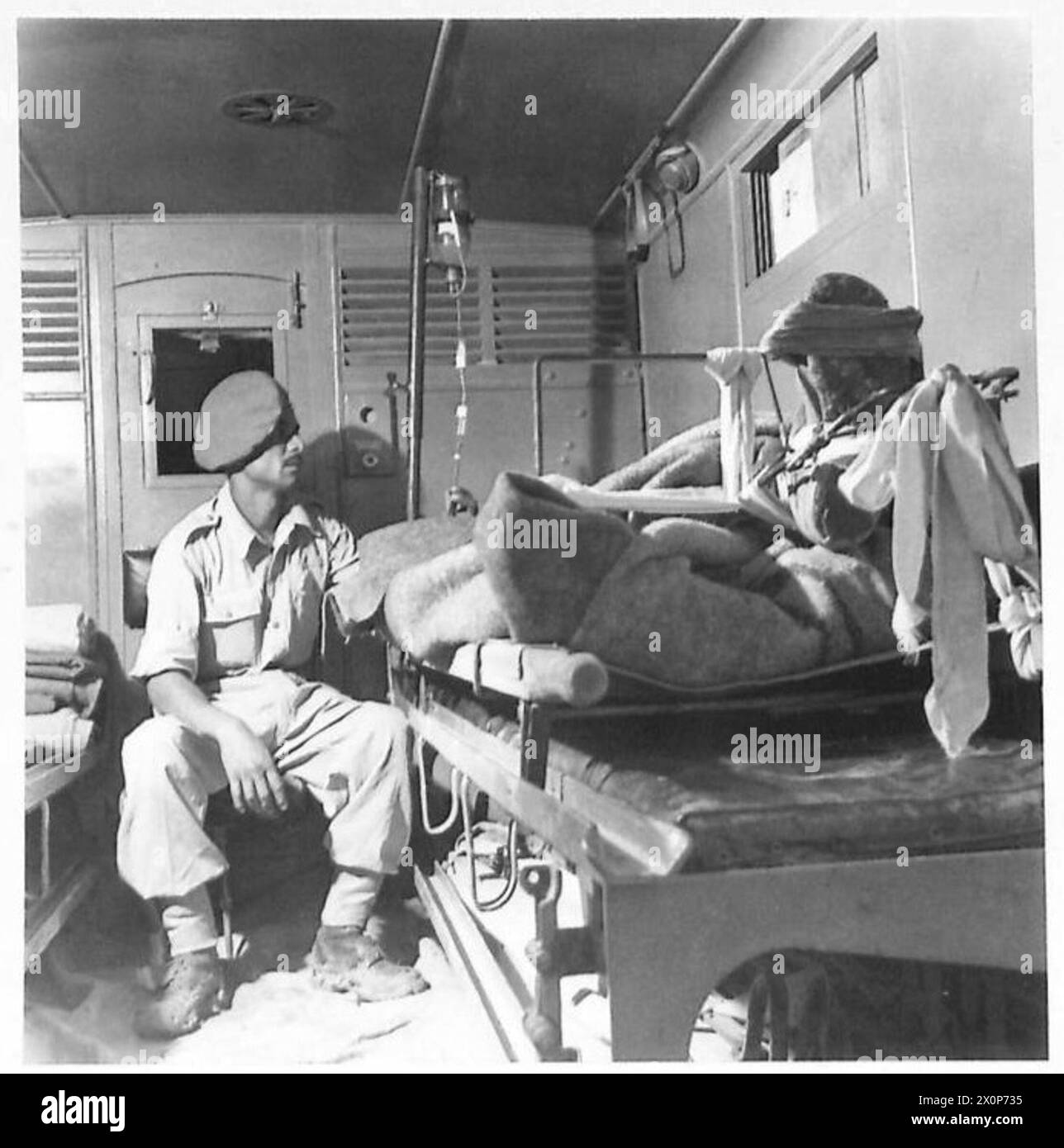 An orderly maintains a plasma drip steady during transport to a Field ...