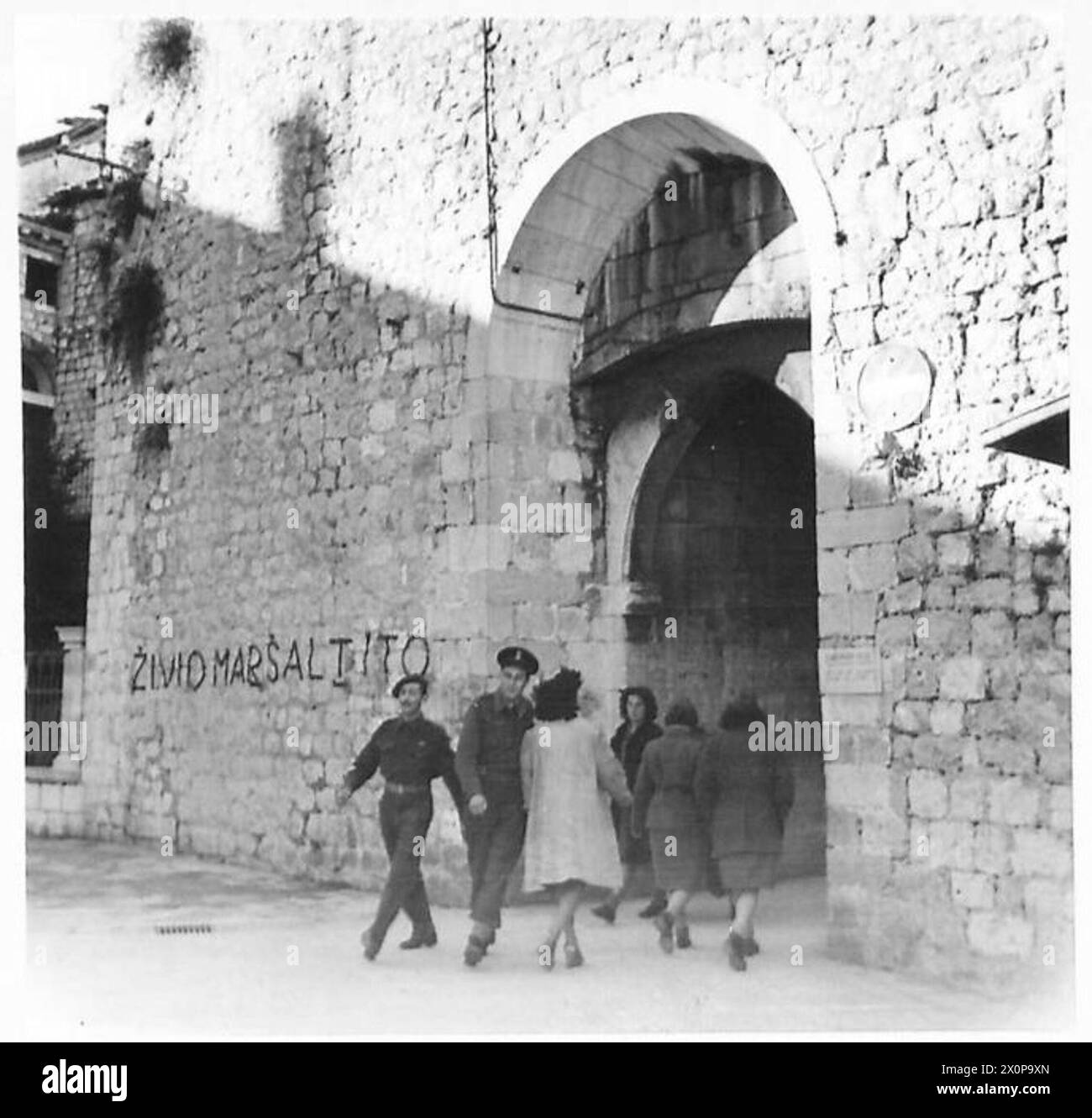 People pass under a series of arches located at both ends of a town in ...