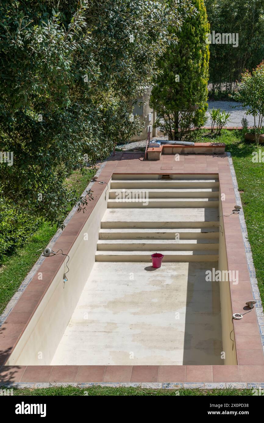 A concrete swimming pool has been emptied for maintenance and is ...