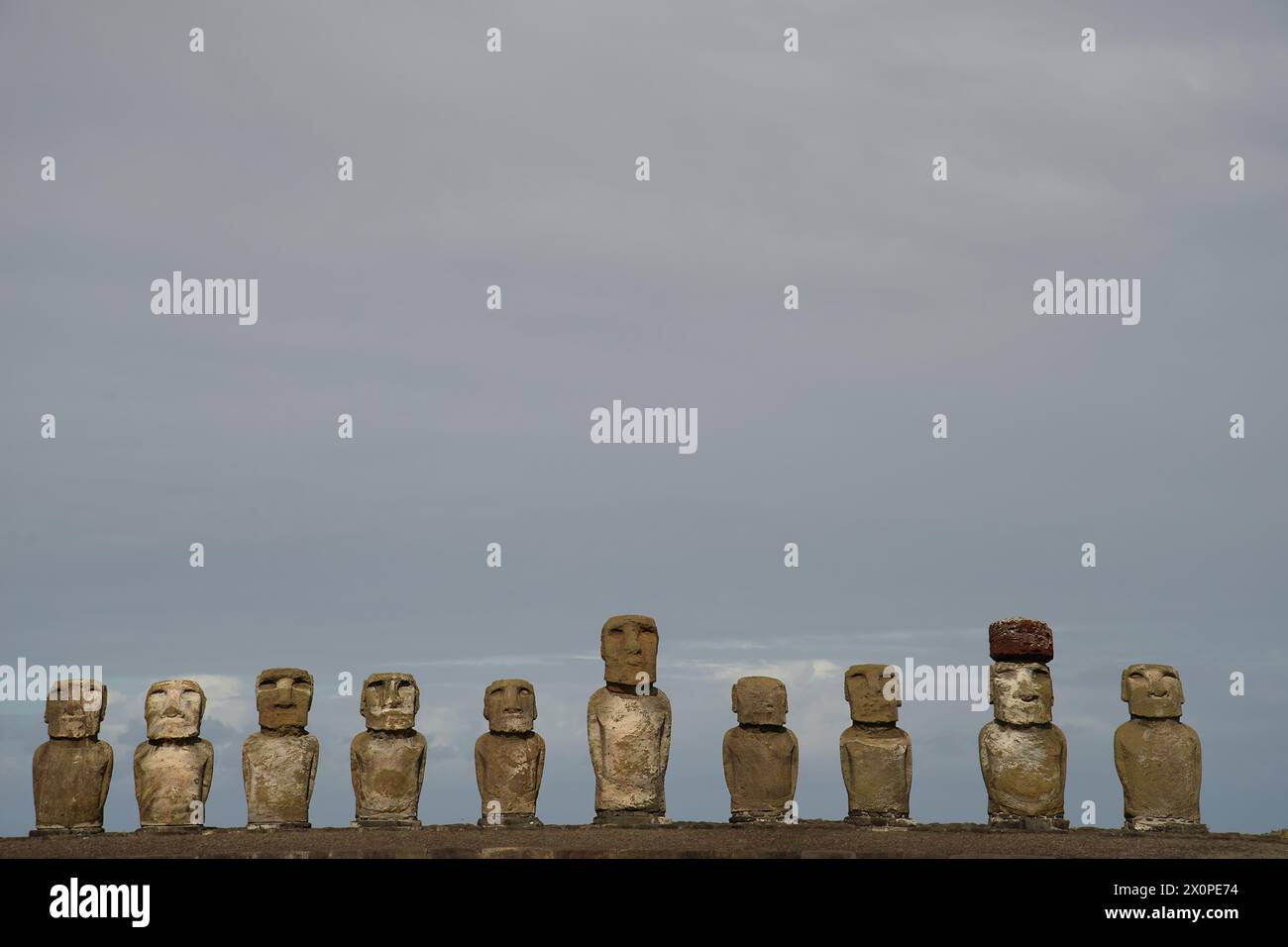 A row of stone statues are lined up on a ledge. The statues are all ...